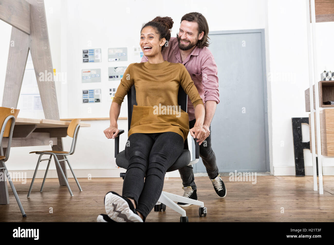 Man pushing happy woman on office chair Stock Photo - Alamy
