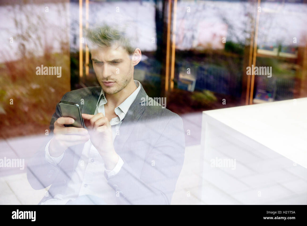 Young man using cell phone in library Stock Photo - Alamy