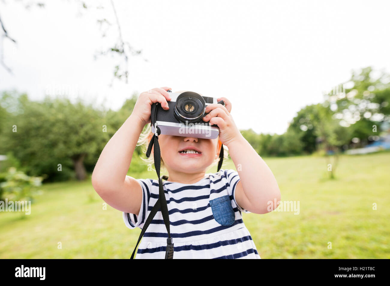 Little girl in park playing with camera Stock Photo - Alamy