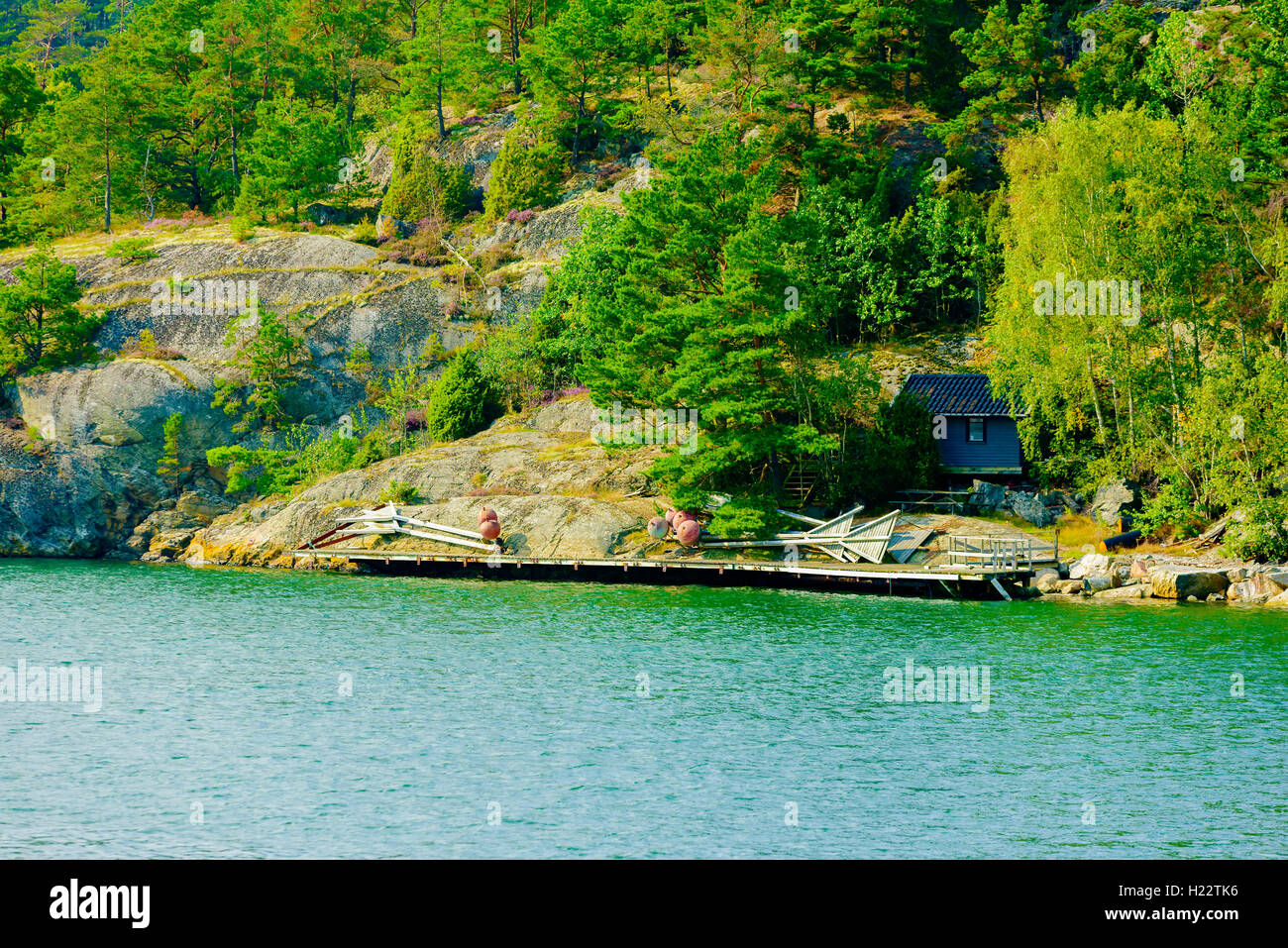 Marine navigational marks on a pier close to a cabin in rocky woodland ...