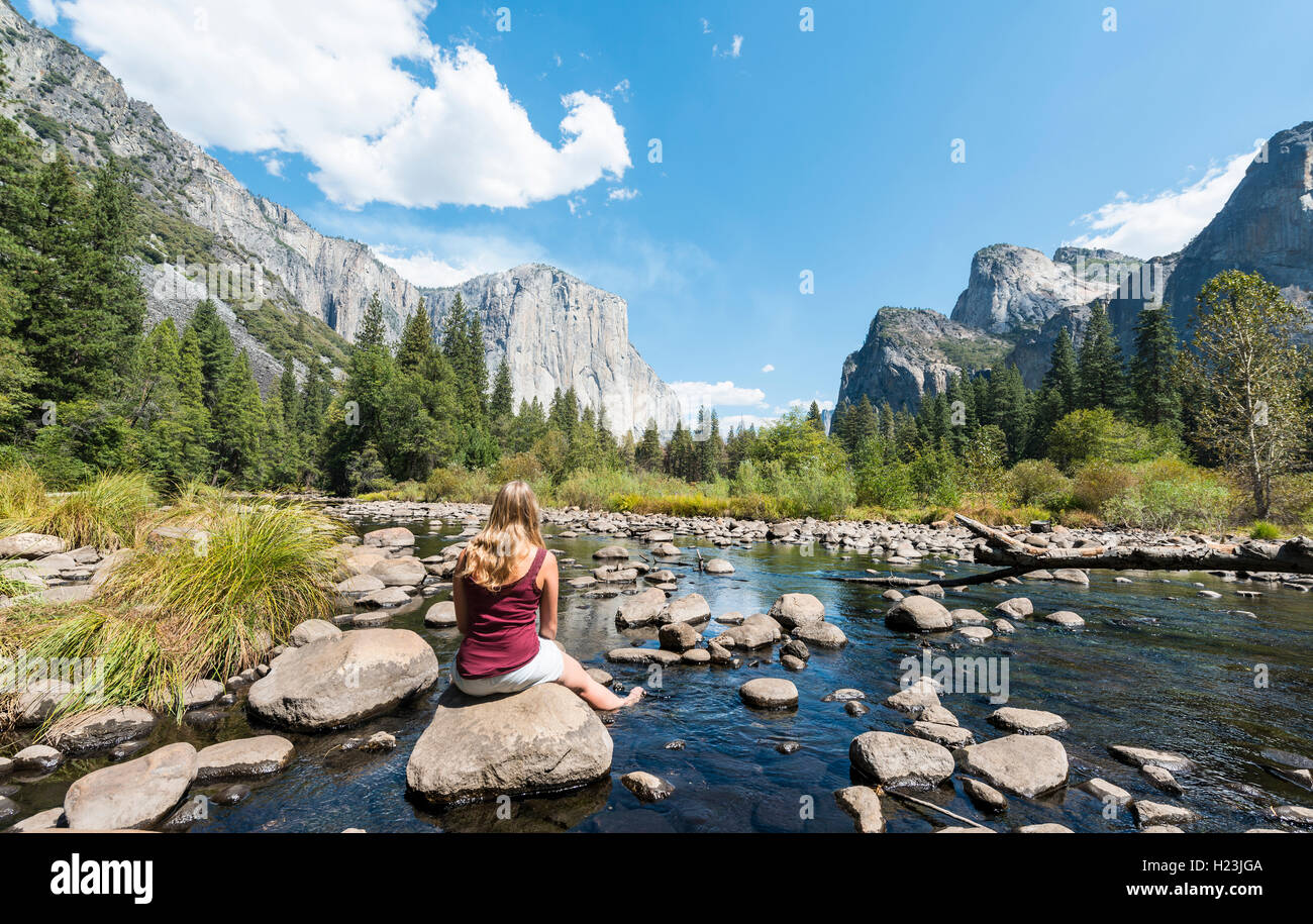 Young woman sitting on stone in River Merced, Valley View, view of El ...