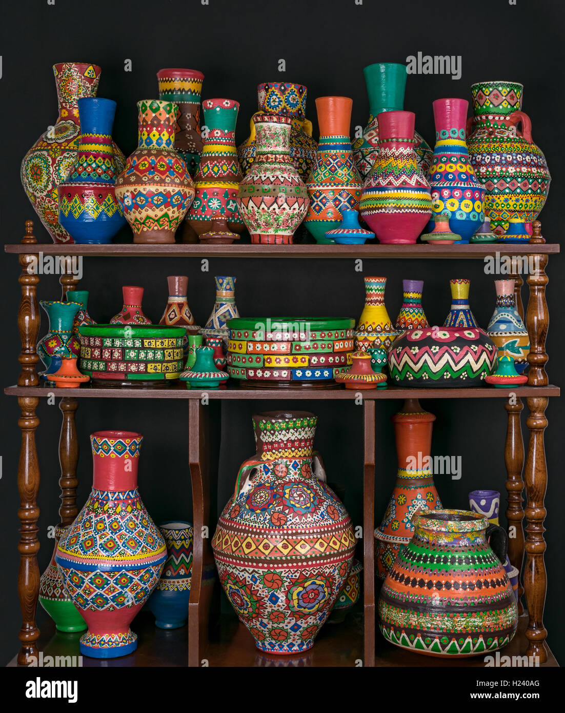 Group of colorful painted pottery crafts stacked in wooden storage ...