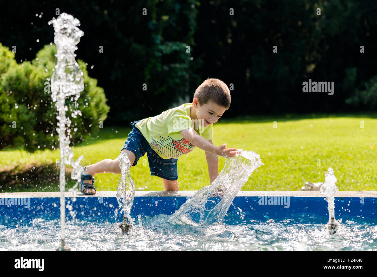 Beautiful boy making splashes in the fountain Stock Photo - Alamy