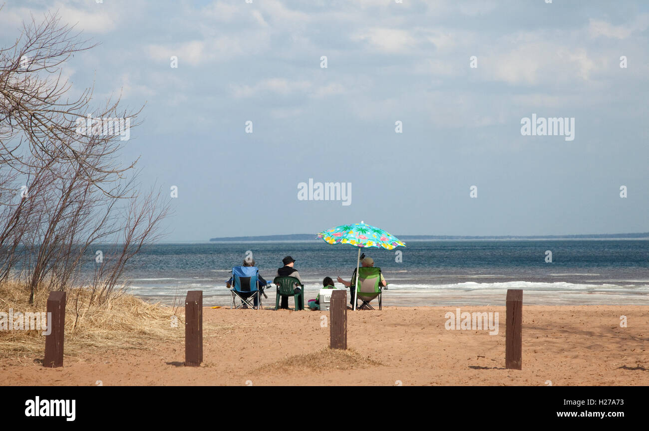 People enjoying Lake superior winter beach with deck chairs, umbrella ...