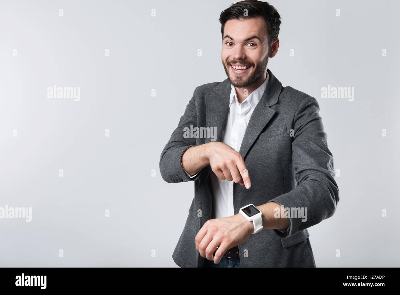 Smiling bearded man pointing on his smart watch Stock Photo - Alamy