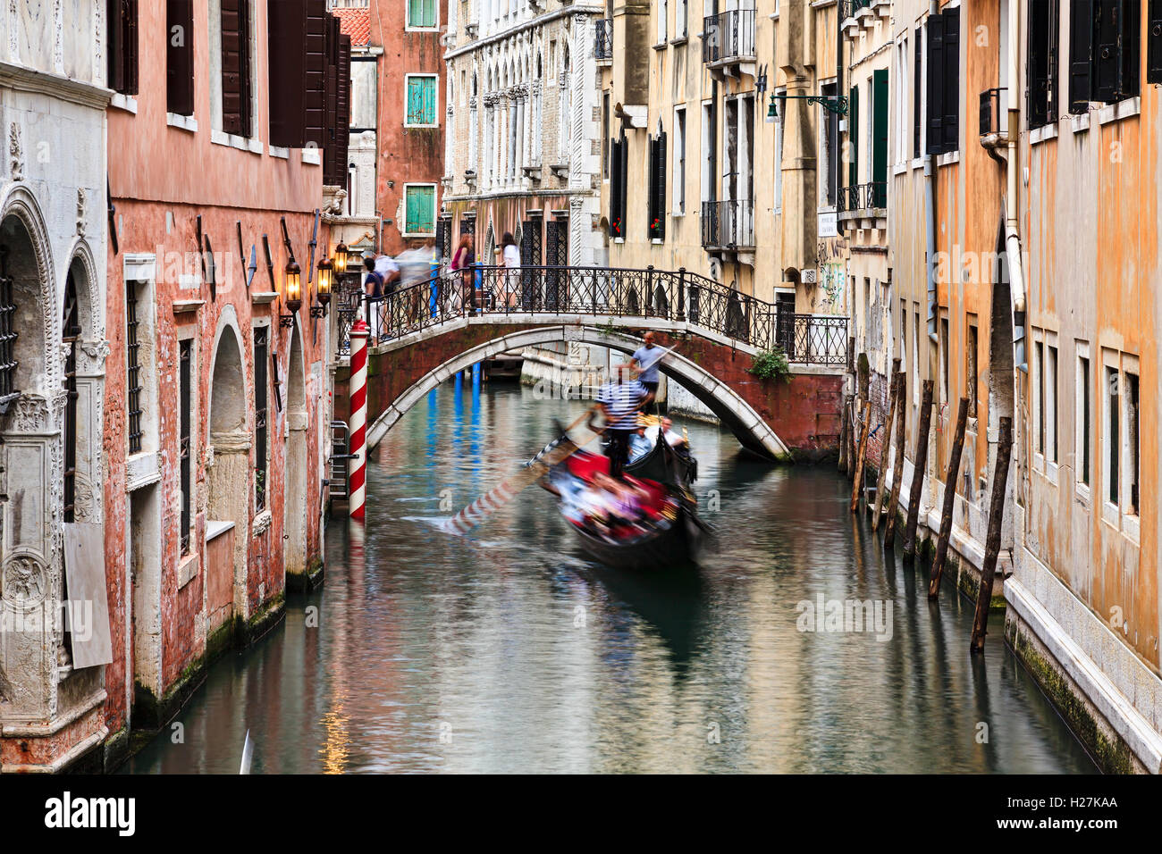 Narrow side canal in Venice with small connecting bridge and floating ...