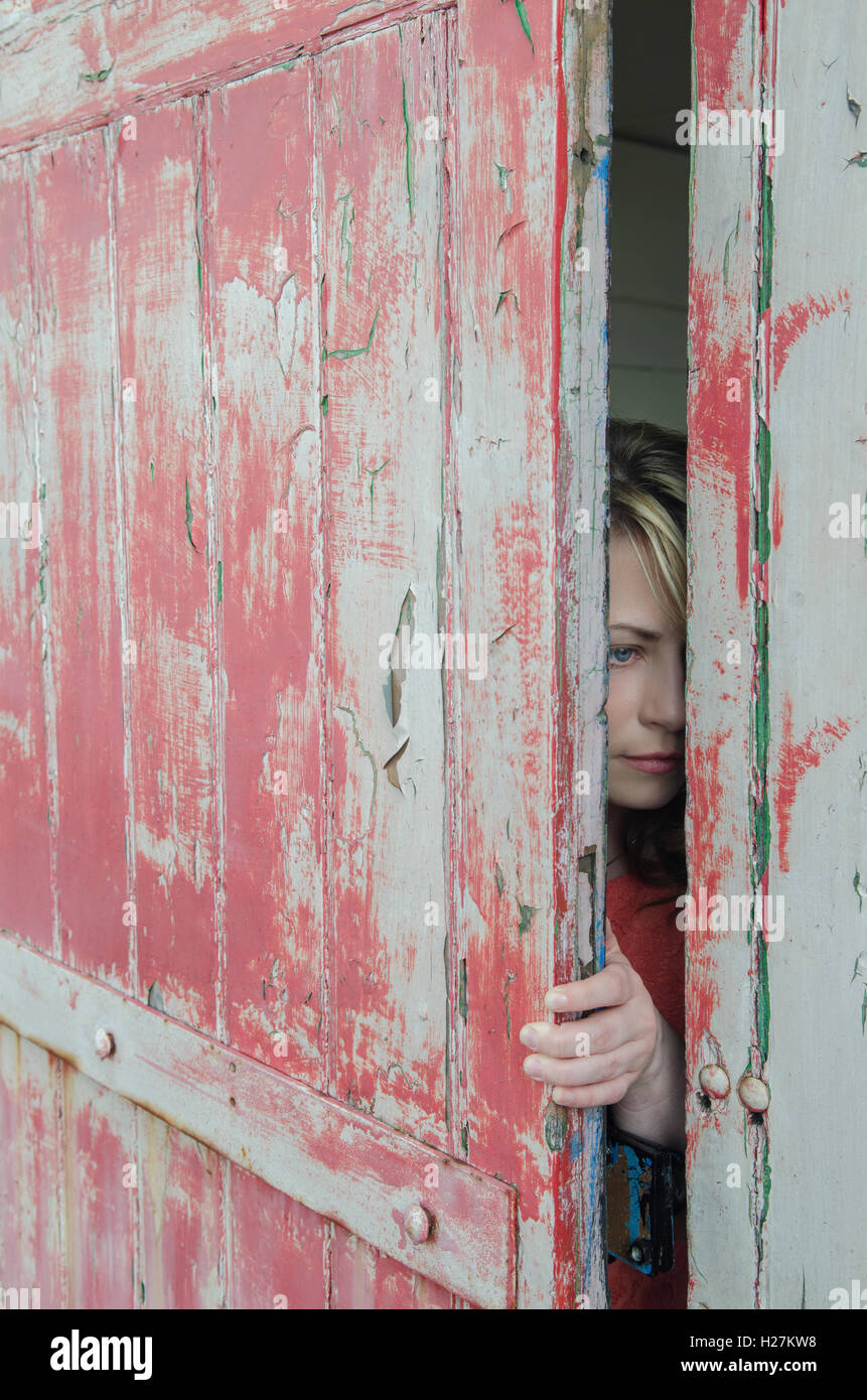 Woman looking through the door Stock Photo - Alamy