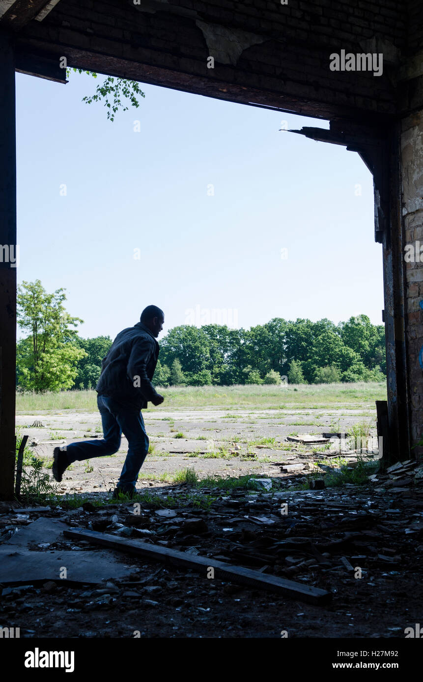 Mysterious male figure running outside a derelict building in the ...