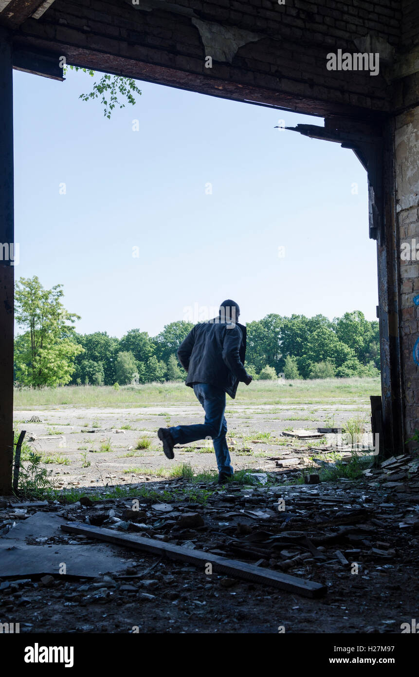 Mysterious male figure running outside a derelict building in the ...