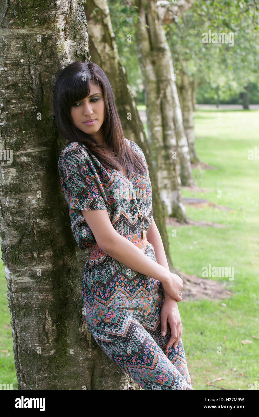 Beautiful young woman leaning against the tree Stock Photo - Alamy