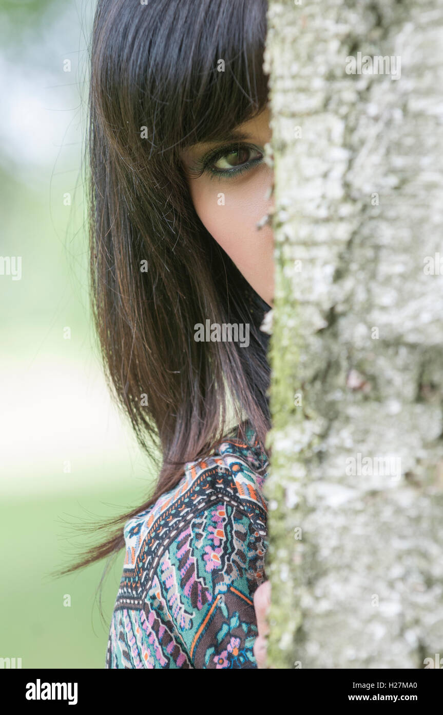 Young woman hiding behind a tree Stock Photo - Alamy