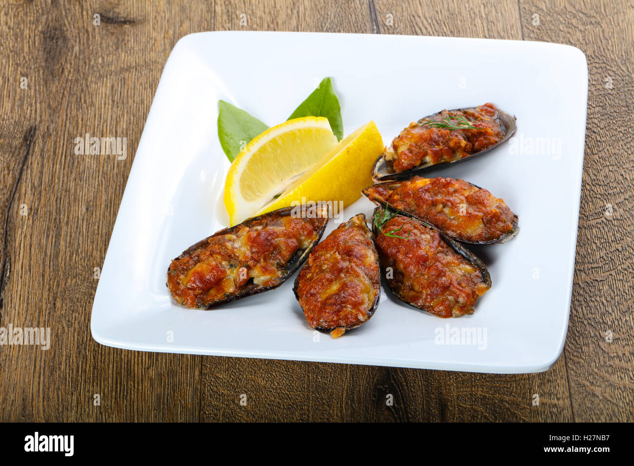 Baked mussels with laurel leaves and lemon Stock Photo - Alamy