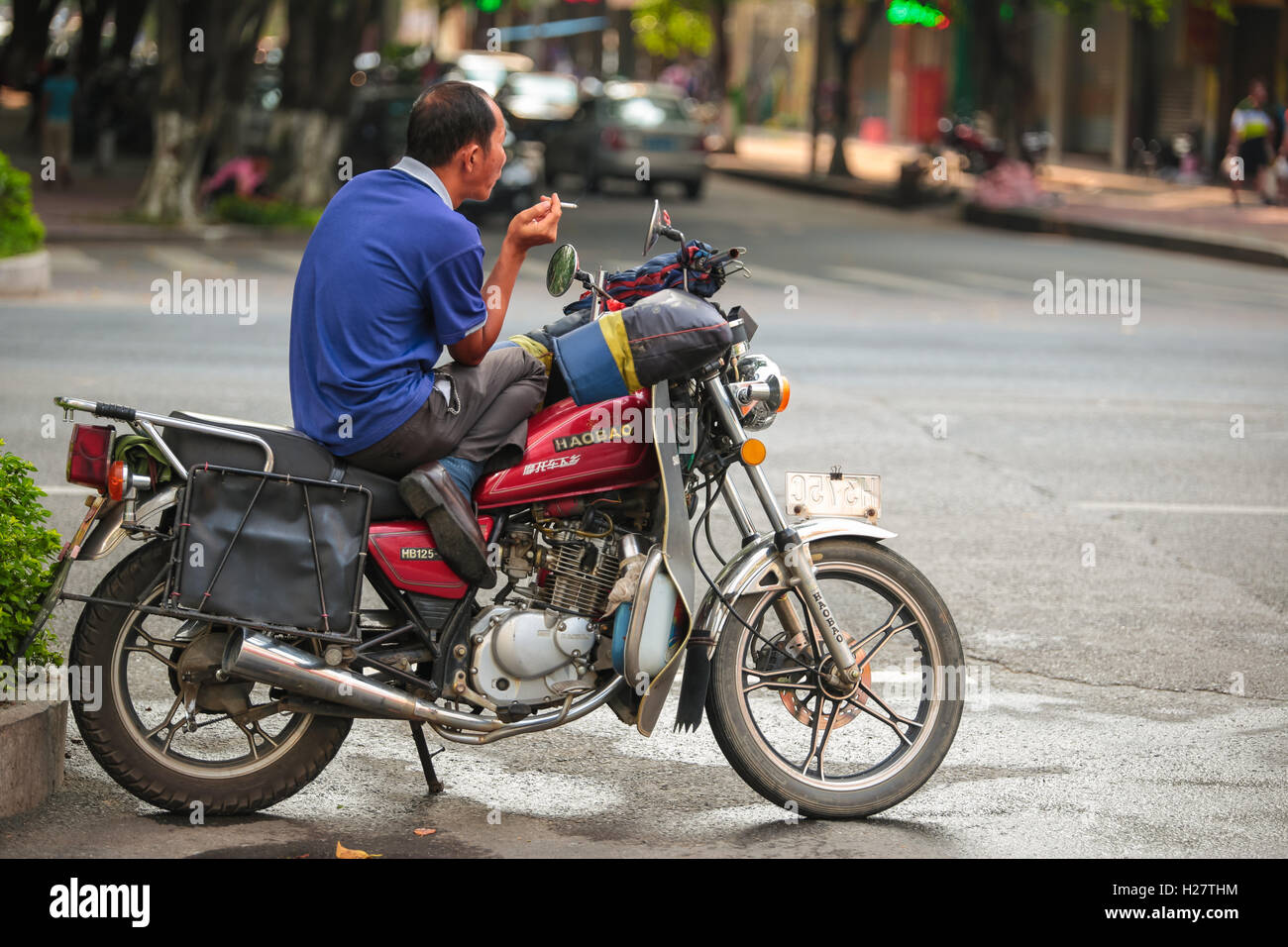 Motorbike taxi rider waiting for customer on the street of Meizhou ...