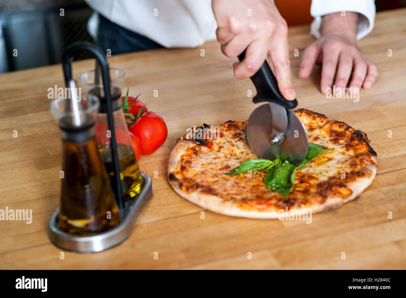 Chef cutting pizza into pieces Stock Photo - Alamy