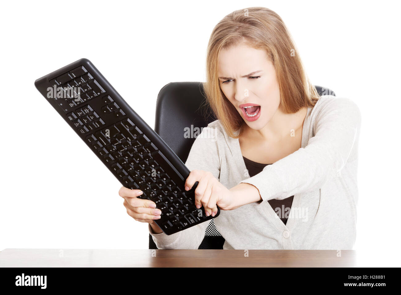 Beautiful casual woman trying to destroy keyboard Stock Photo - Alamy
