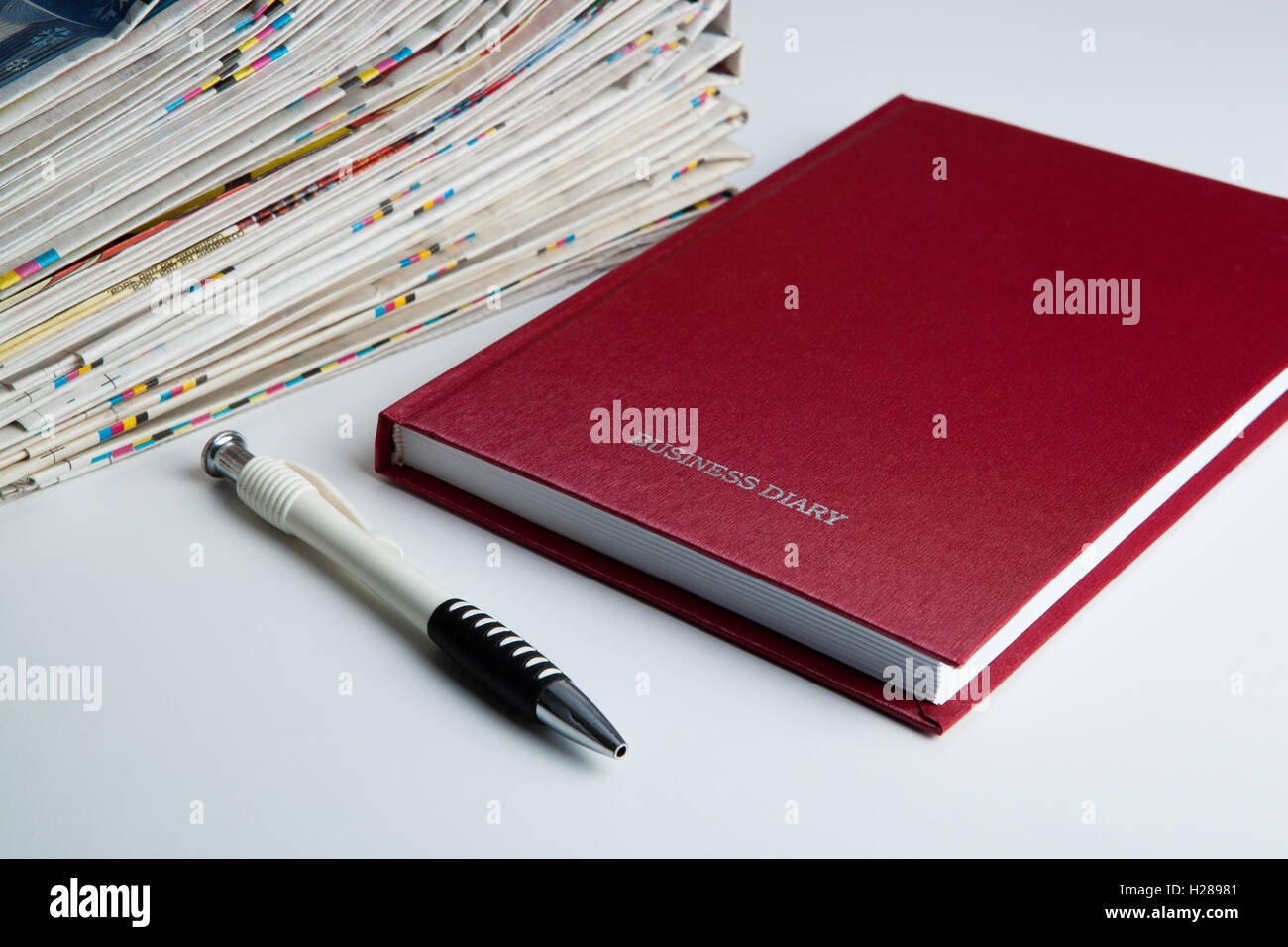 business diary with pen and stack of newspapers Stock Photo - Alamy