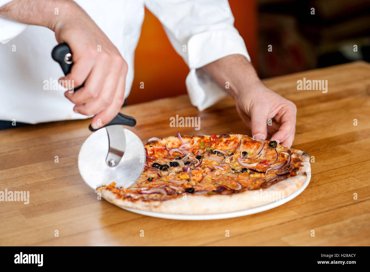 Chef cutting pizza with cutter Stock Photo - Alamy