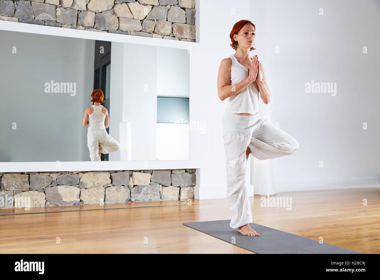Yoga one leg balance Tree pose on wooden floor gym and mirror indoor ...