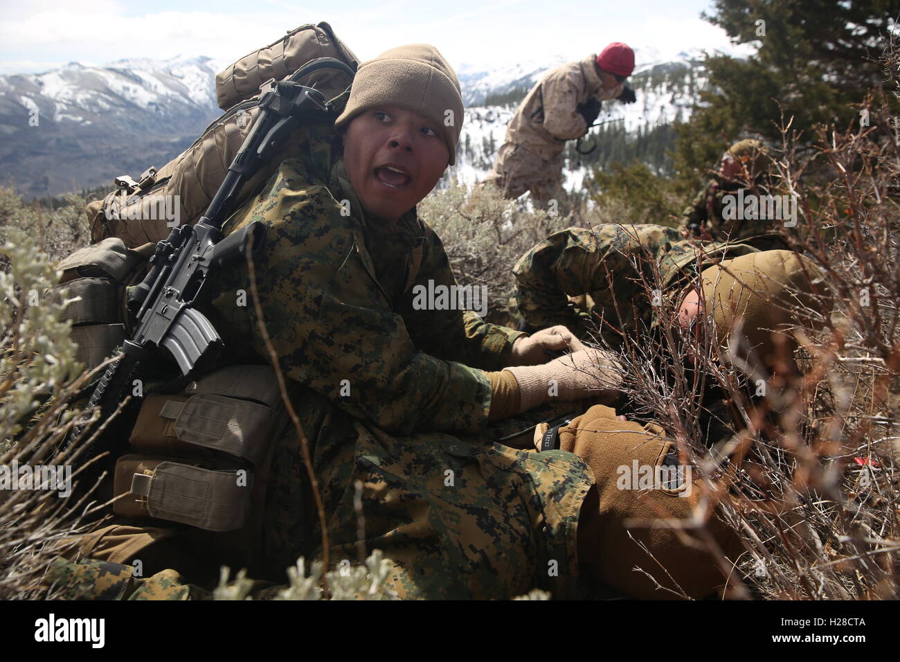 A U.S. Marine provides first aid to a soldier while directing teams ...
