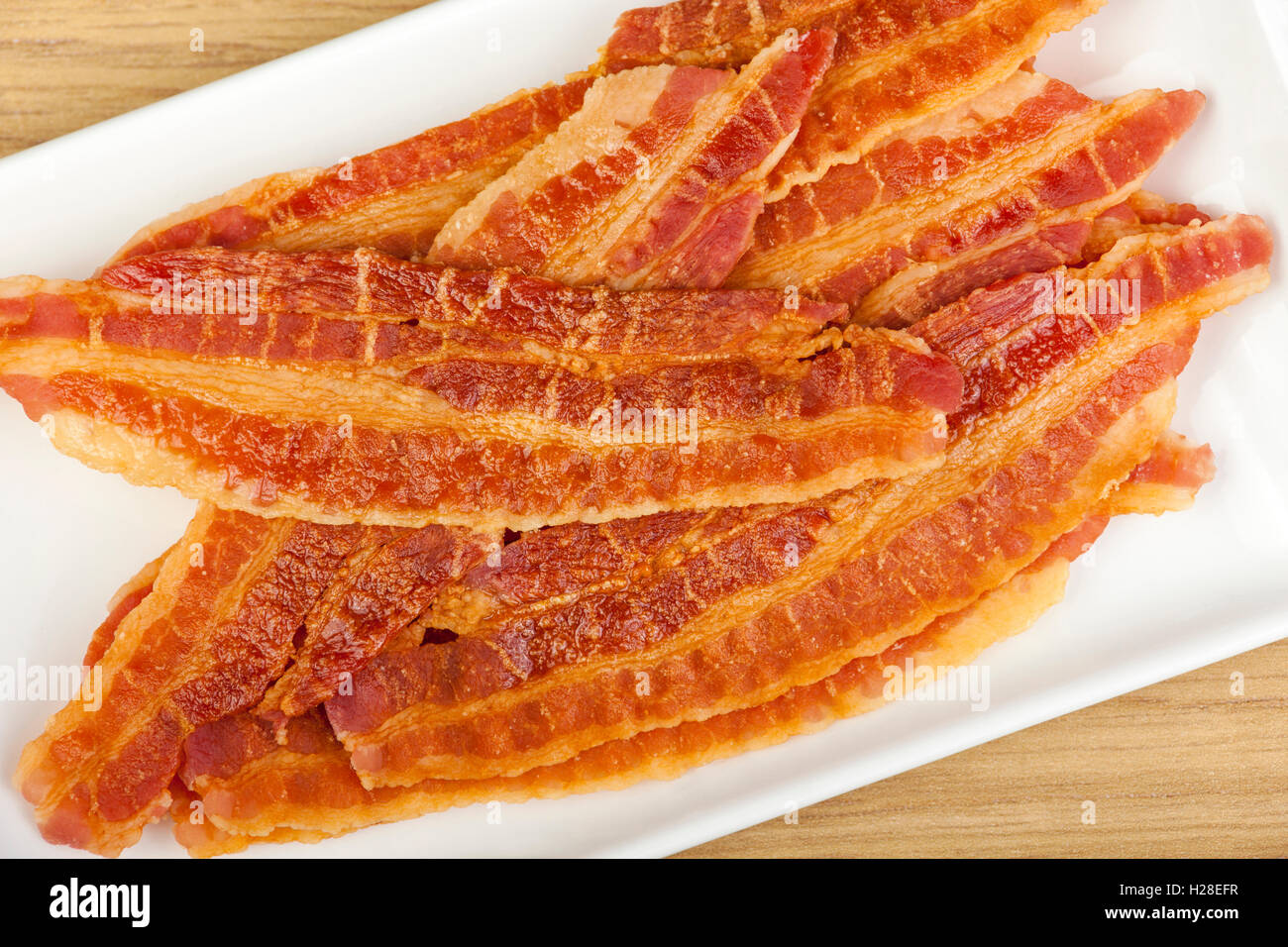 Crispy fresh fried bacon rashers prepared on a white rectangular ...