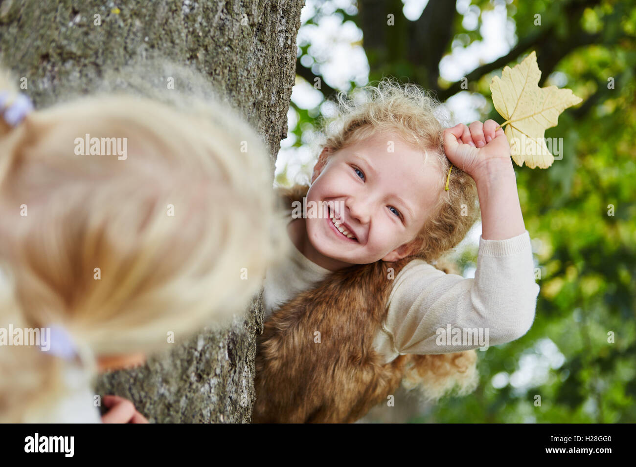 Two kids playing hide and seek at the park in autumn Stock Photo - Alamy