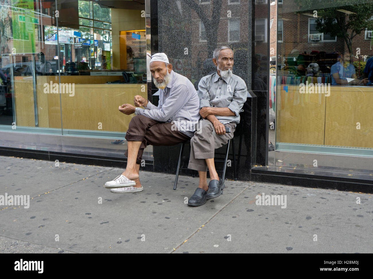 Two Asian Muslim merchants share a chair while minding their stands on ...