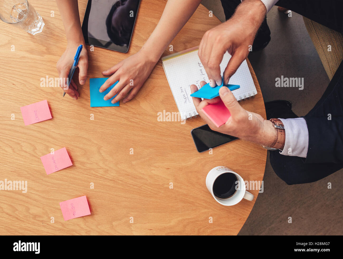Top view of two business people sitting around a table and writing on ...