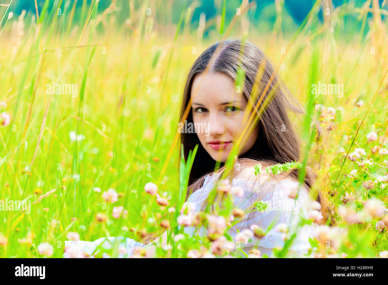 girl in a white sundress lying on green grass Stock Photo - Alamy