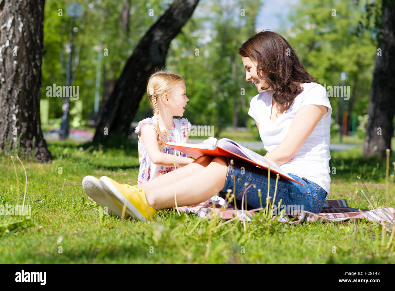 girl and a young woman reading a book together Stock Photo - Alamy