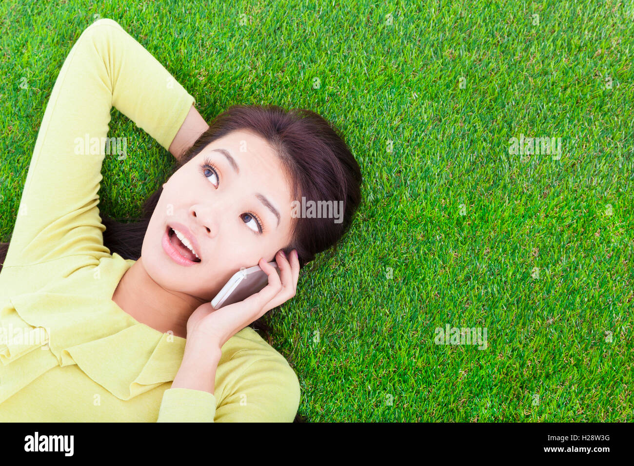 smiling young woman listening with cell phone on grassland Stock Photo ...