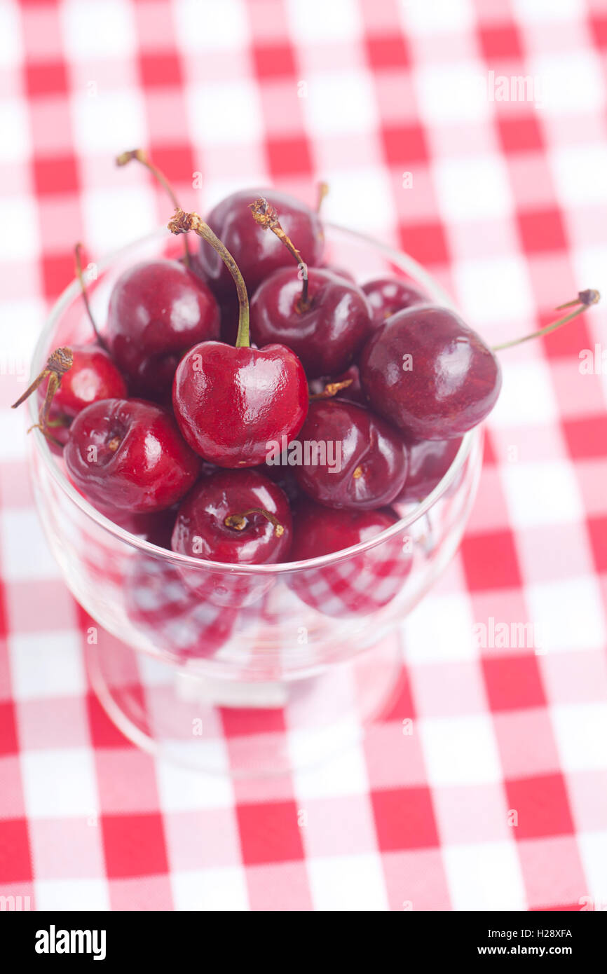 Cherries in a glass bowl on checkered fabric Stock Photo - Alamy