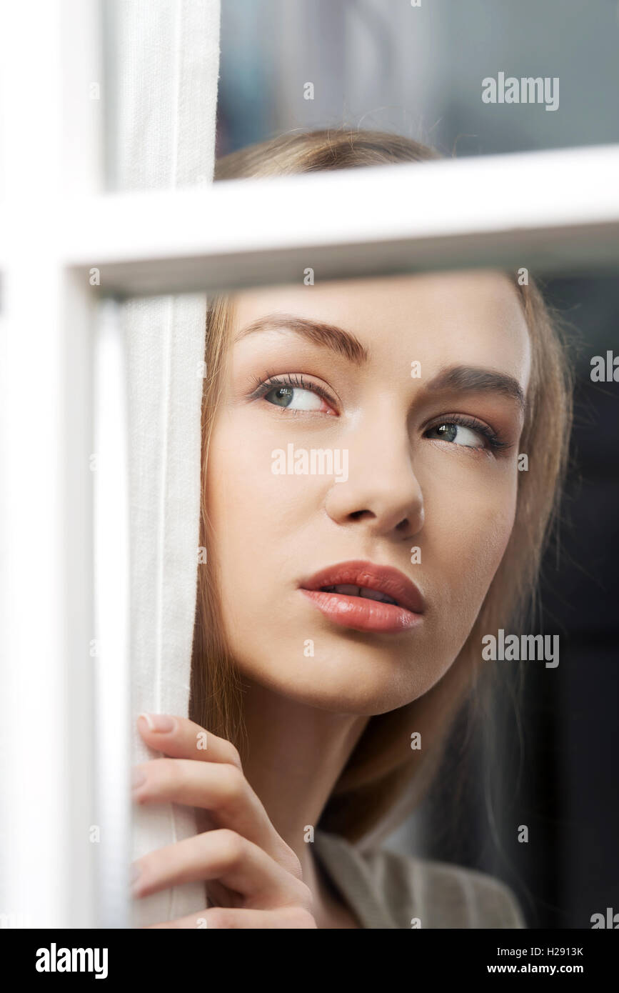 Beautiful woman is looking through window Stock Photo - Alamy