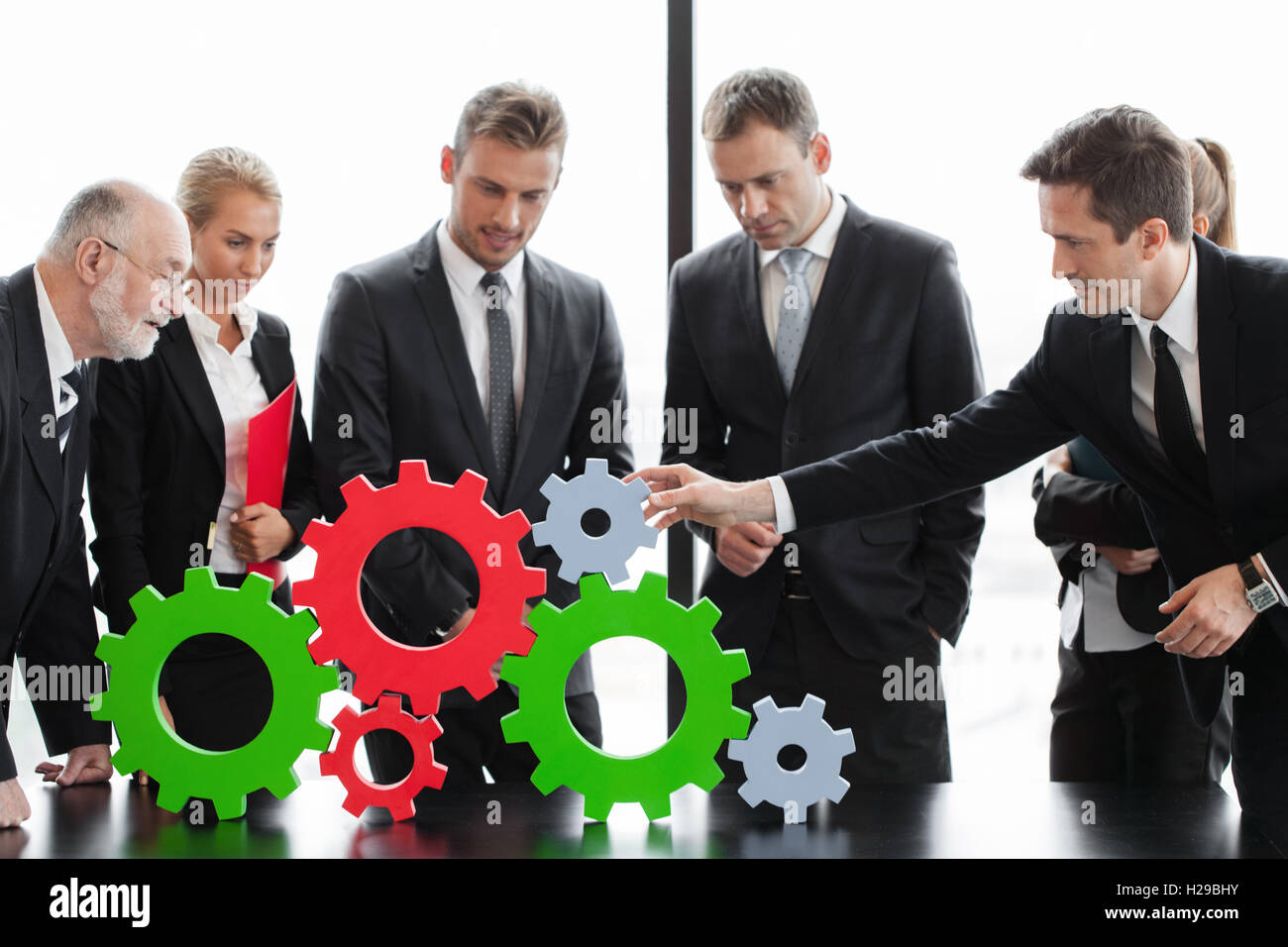 Business people assembling cogwheels, teamwork concept Stock Photo - Alamy