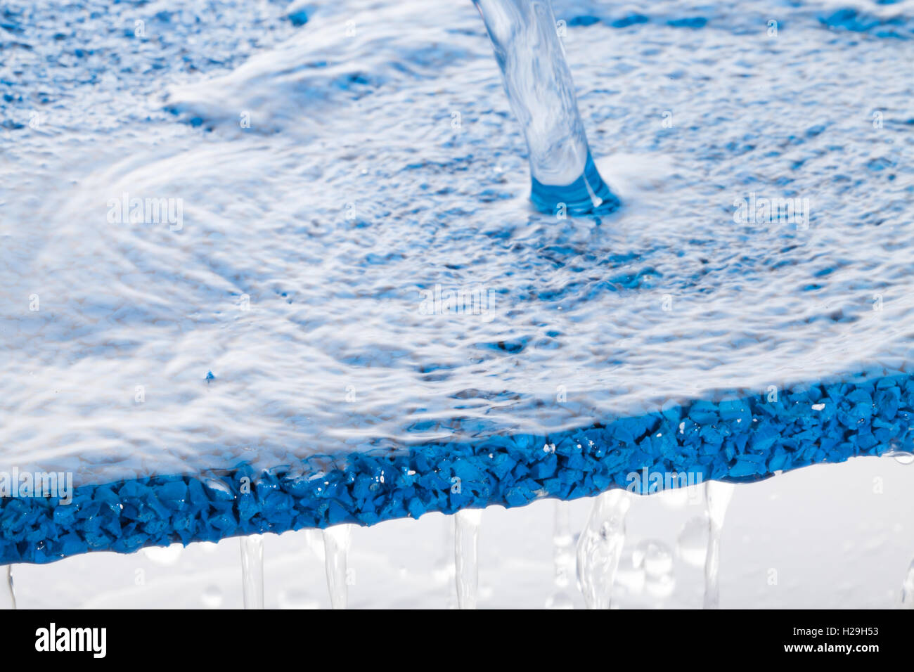 Rubber crumb surface with water pouring through Stock Photo - Alamy