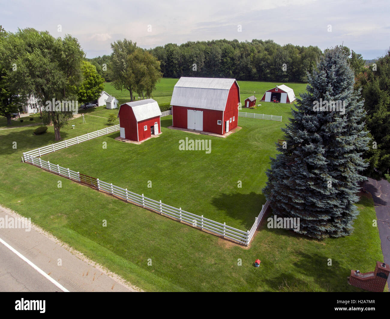 Aerial view of a small red barn surrounded with a white fence near ...