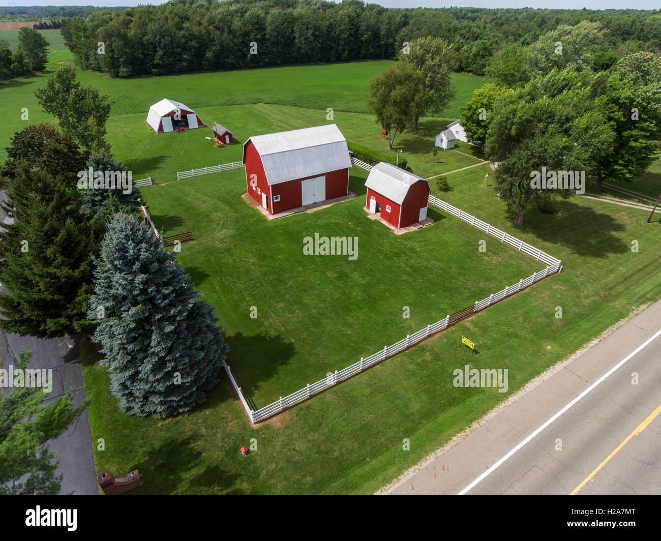 Aerial view of a small red barn surrounded with a white fence near ...