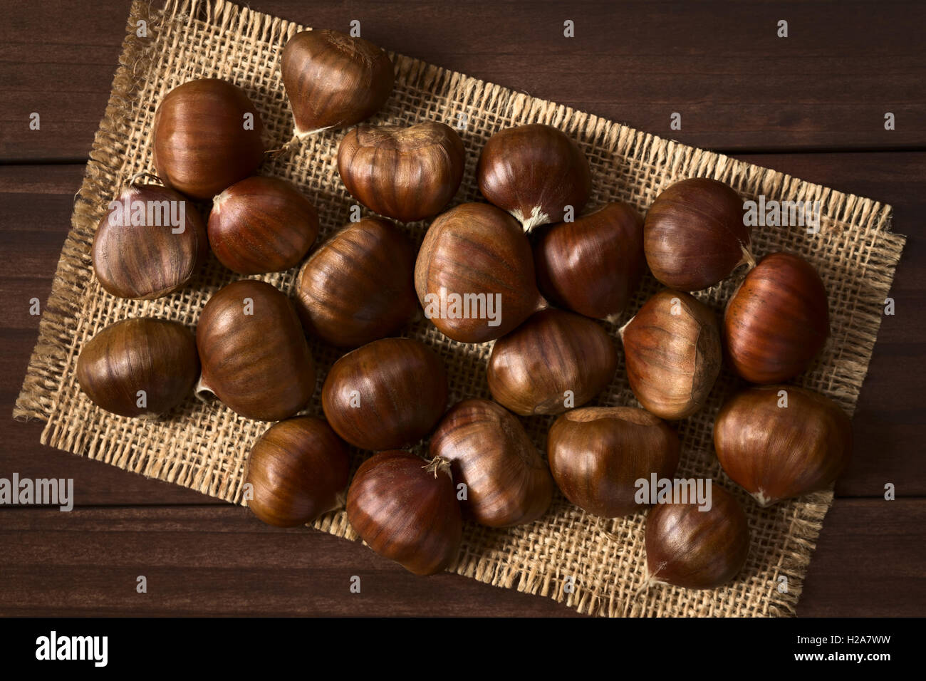 Fresh raw chestnuts, photographed overhead on wood with natural light ...