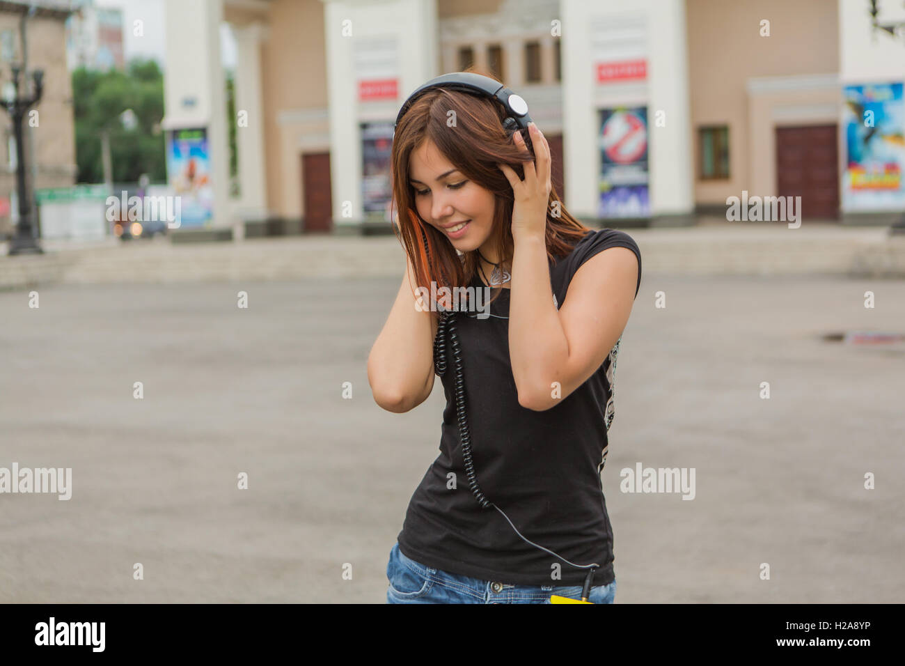 Beautiful asian girl listening to music with headphones on the street ...