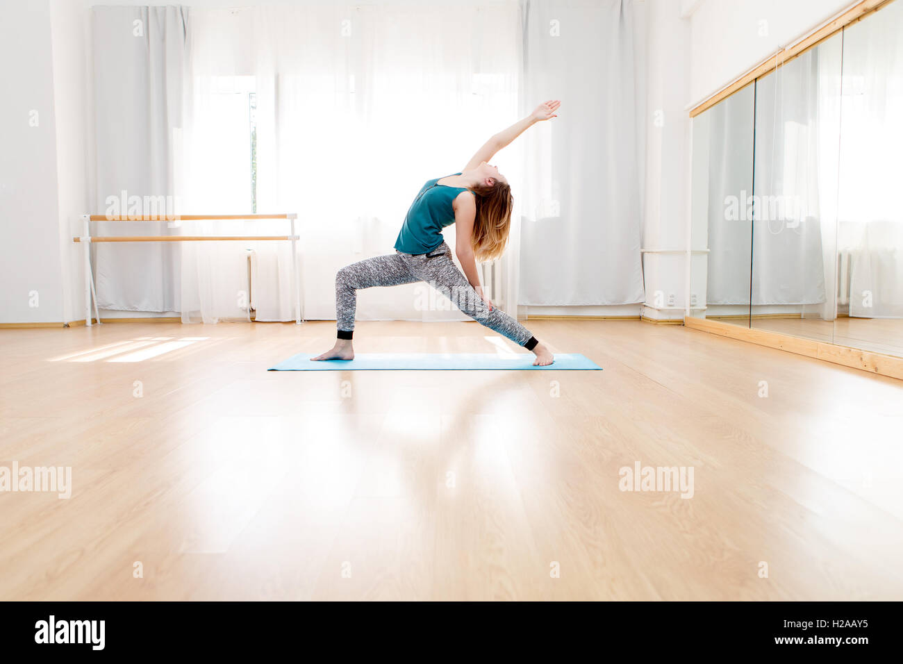 Woman doing high lunge yoga asana in light spacious studio Stock Photo ...