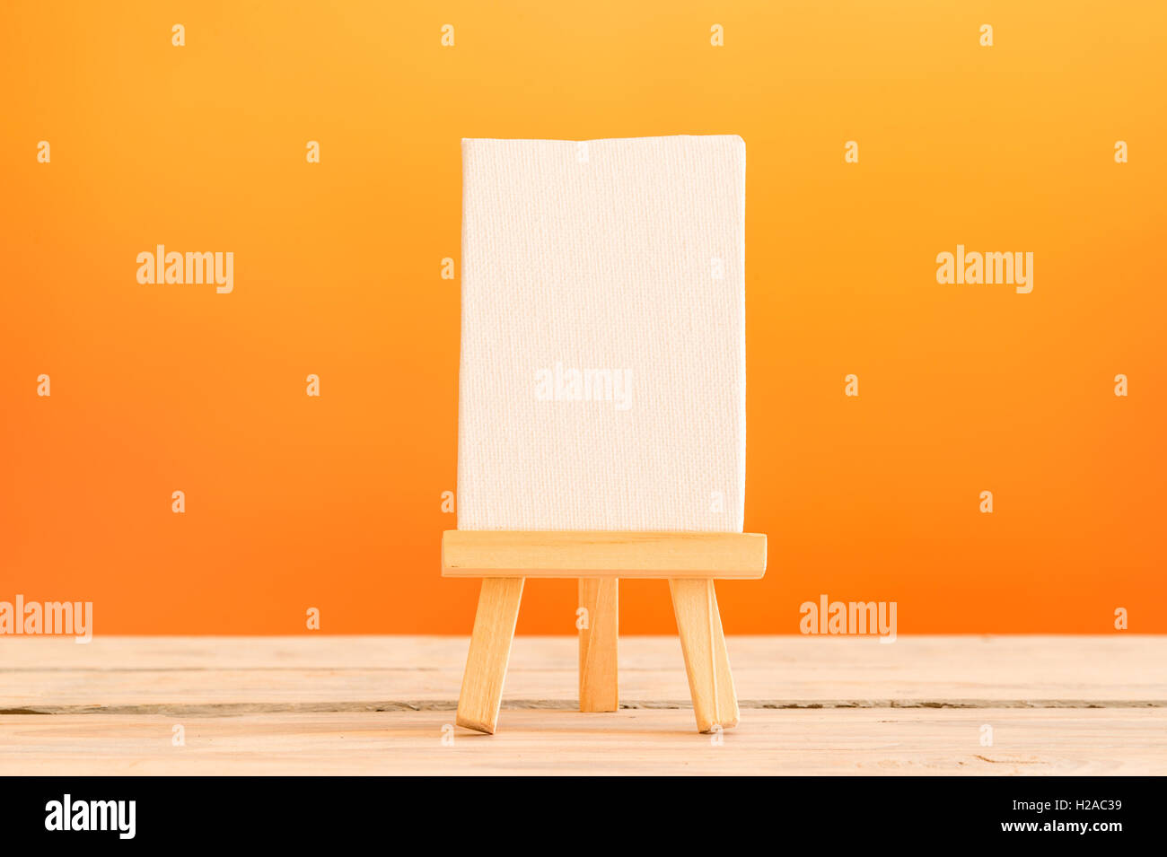 Canvas on a tripod on a table with orange background Stock Photo - Alamy