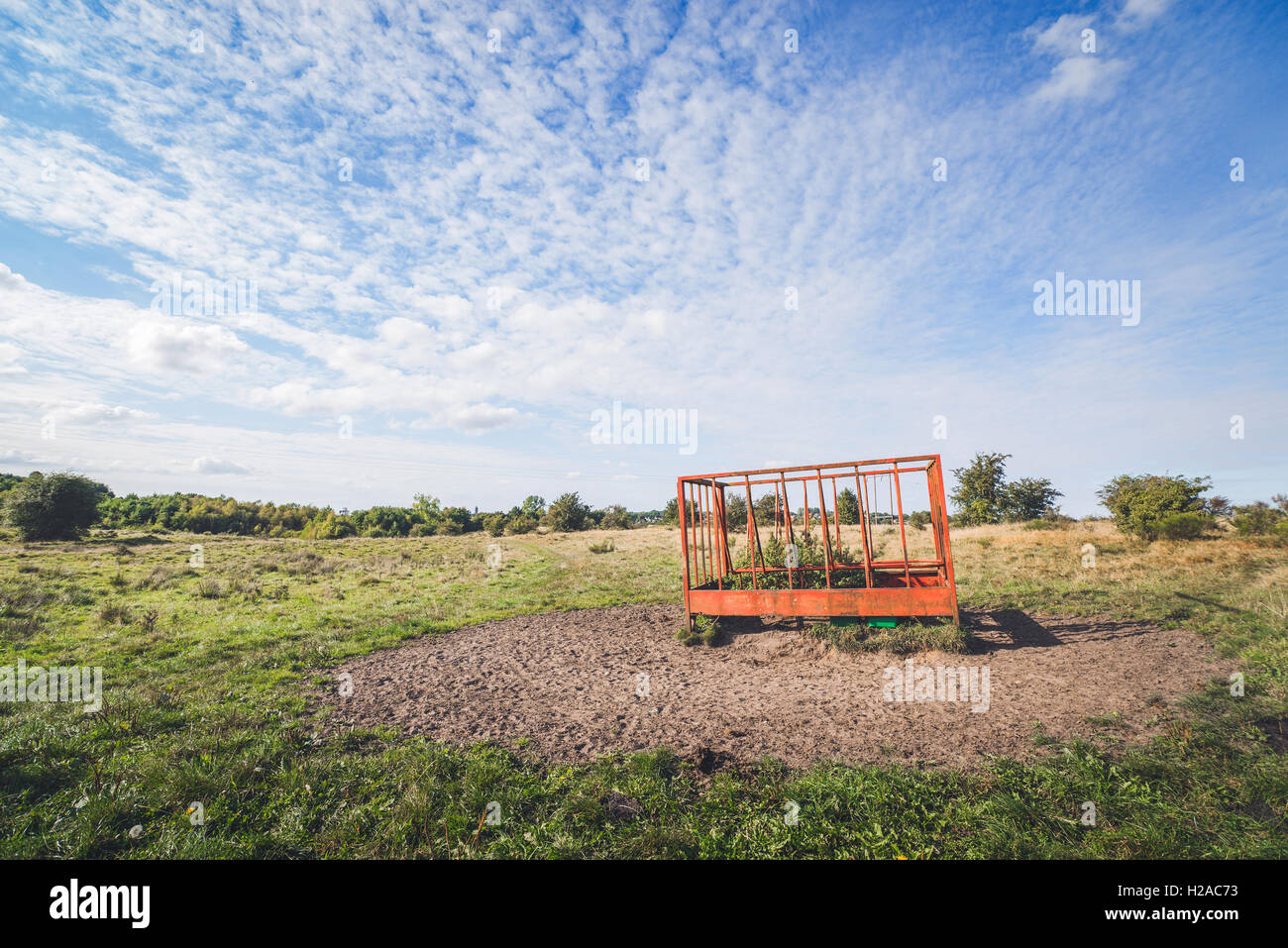 Rural field with a red cage in a countryside landscape Stock Photo - Alamy