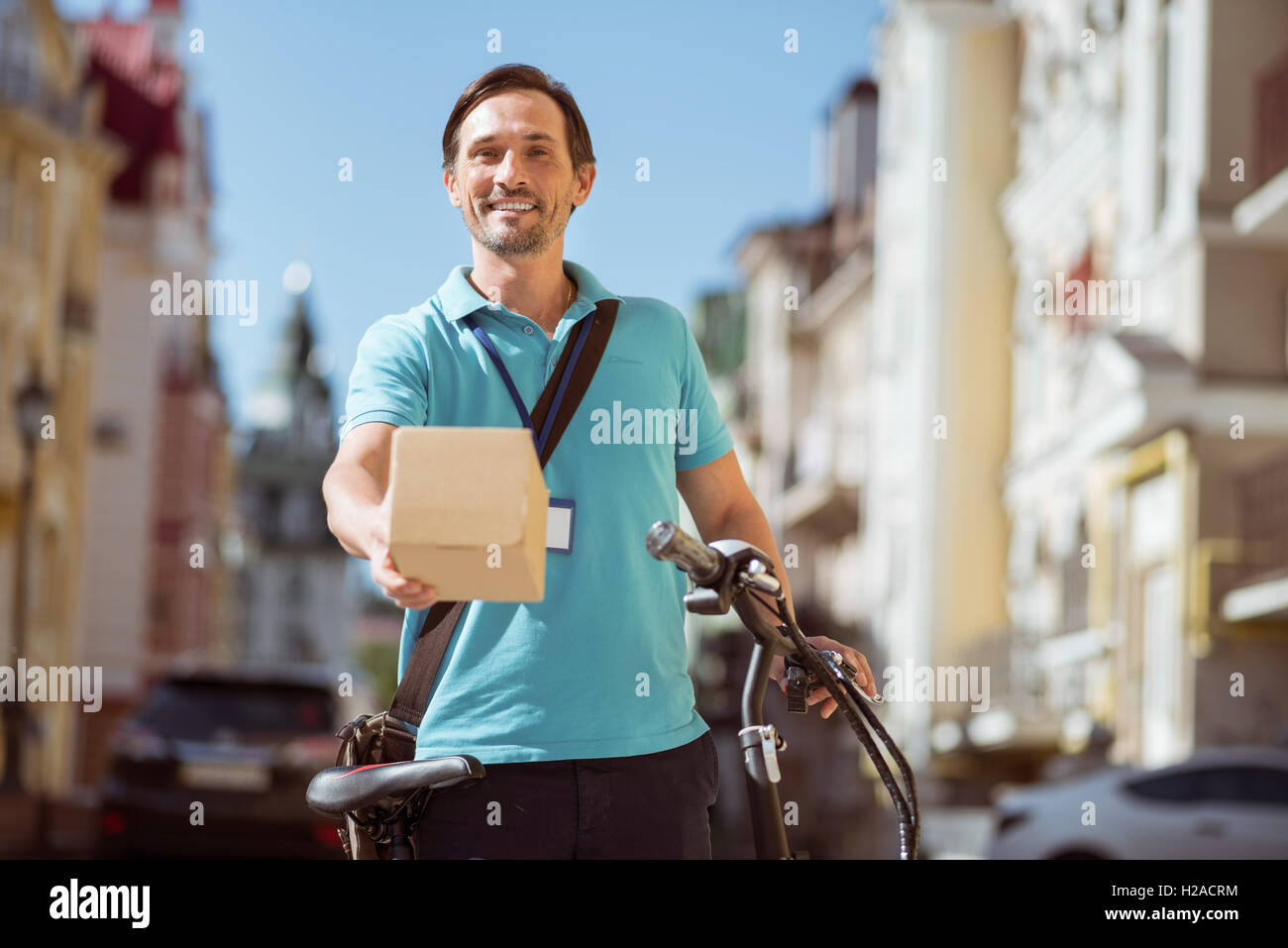 Cheerful professional courier delivering the box Stock Photo - Alamy