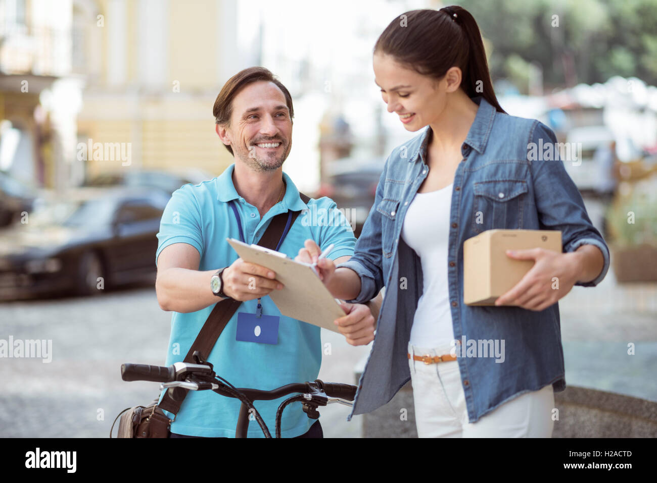 Positive client signing paper of the courier Stock Photo - Alamy