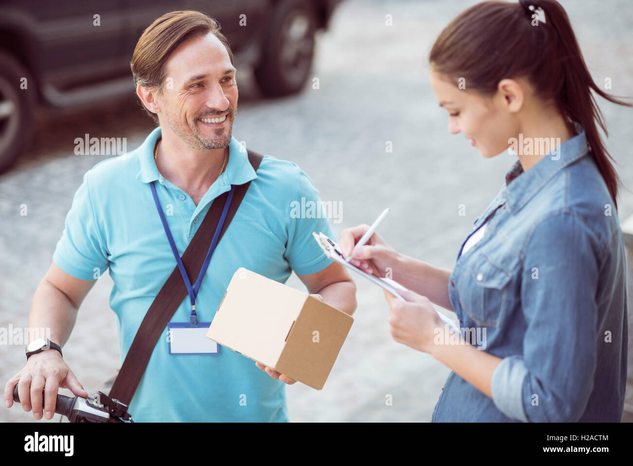 Positive professional courier delivering the parcel Stock Photo - Alamy