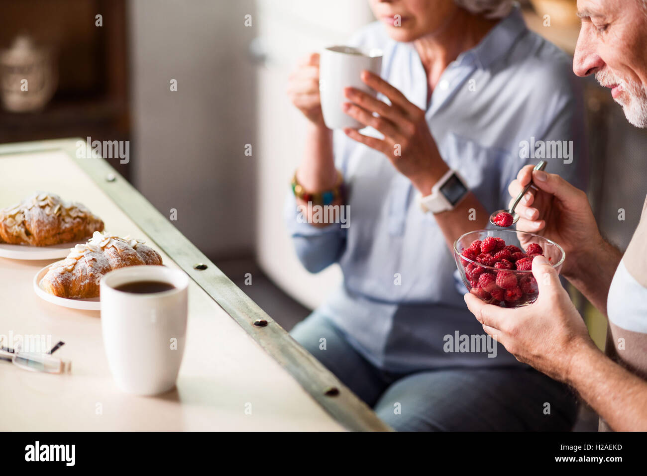 Two people eating raspberry at the kitchen Stock Photo - Alamy