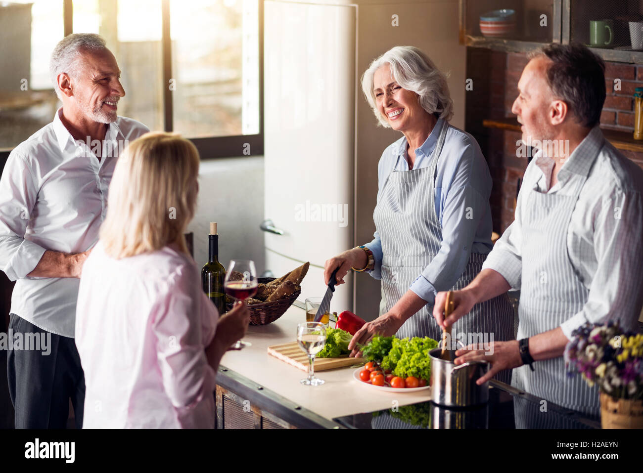 Four nice elderly people gathered around table in kitchen Stock Photo ...