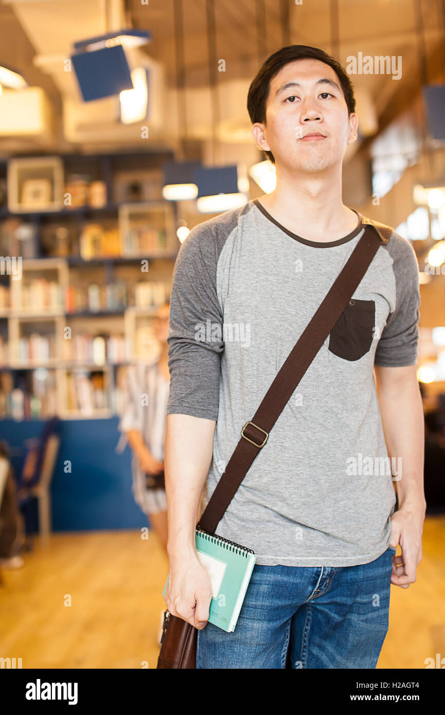 Young Asian college man standing in school library Stock Photo - Alamy