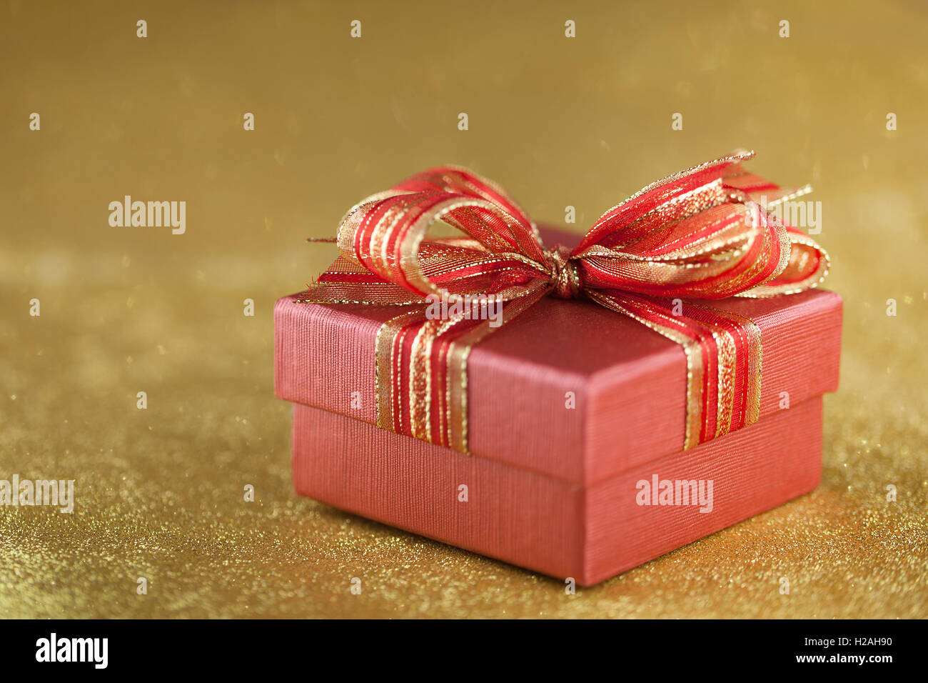 red gift box on glitter gold background Stock Photo - Alamy