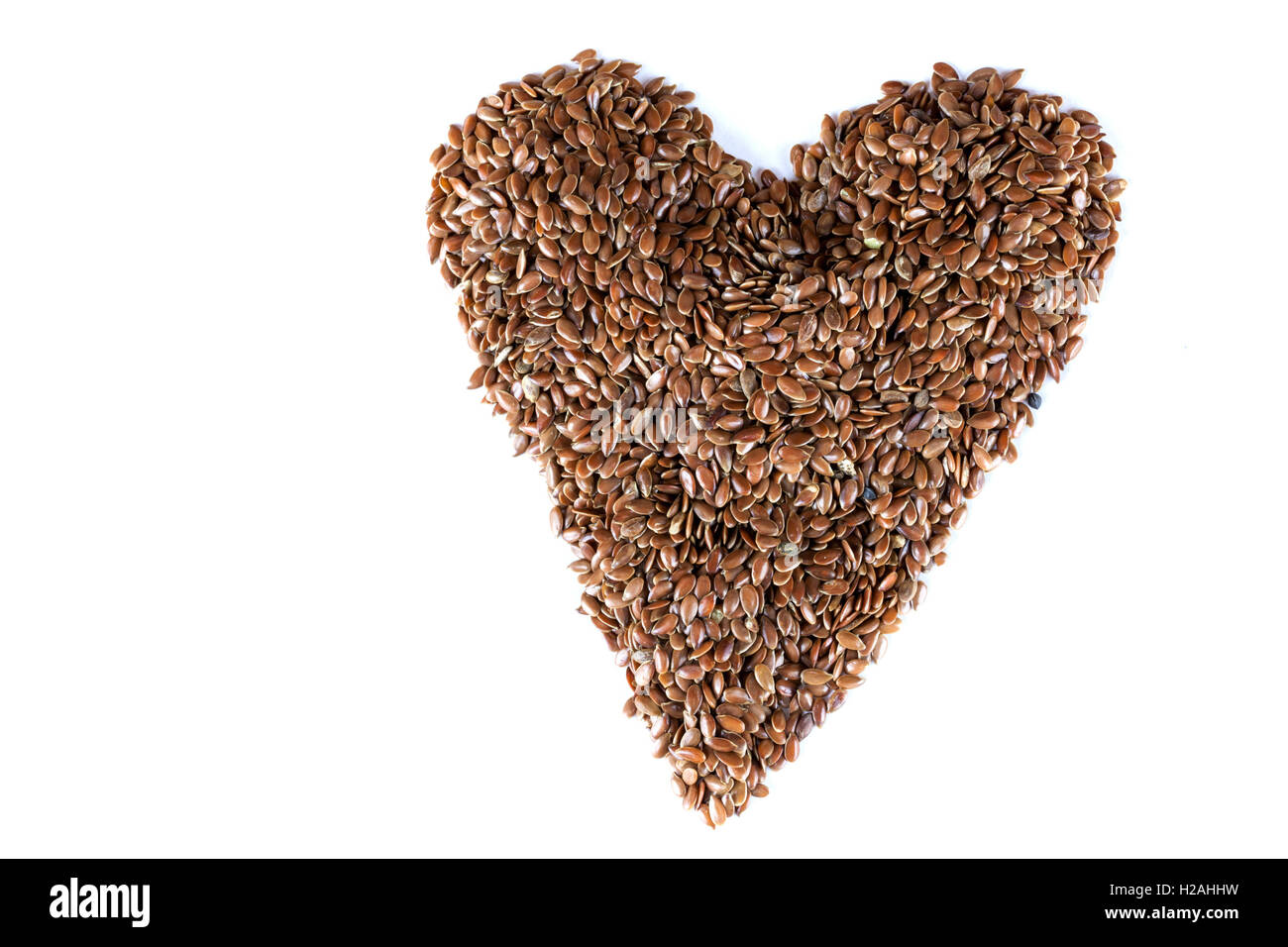 a pile of brown flax seeds in heart shape form on isolated white background Stock Photo - Alamy