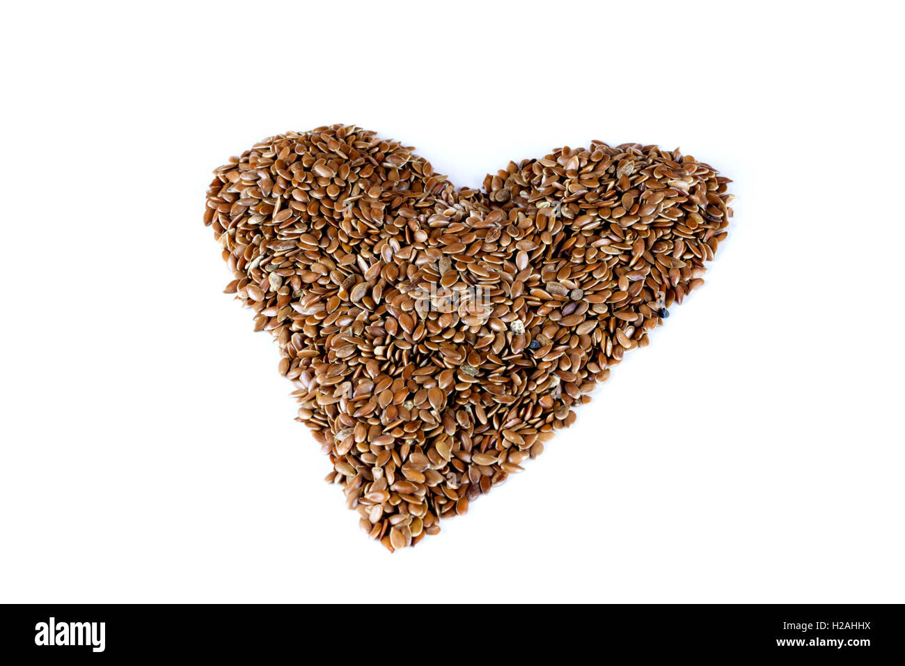 a pile of brown flax seeds in heart shape form on isolated white background Stock Photo - Alamy